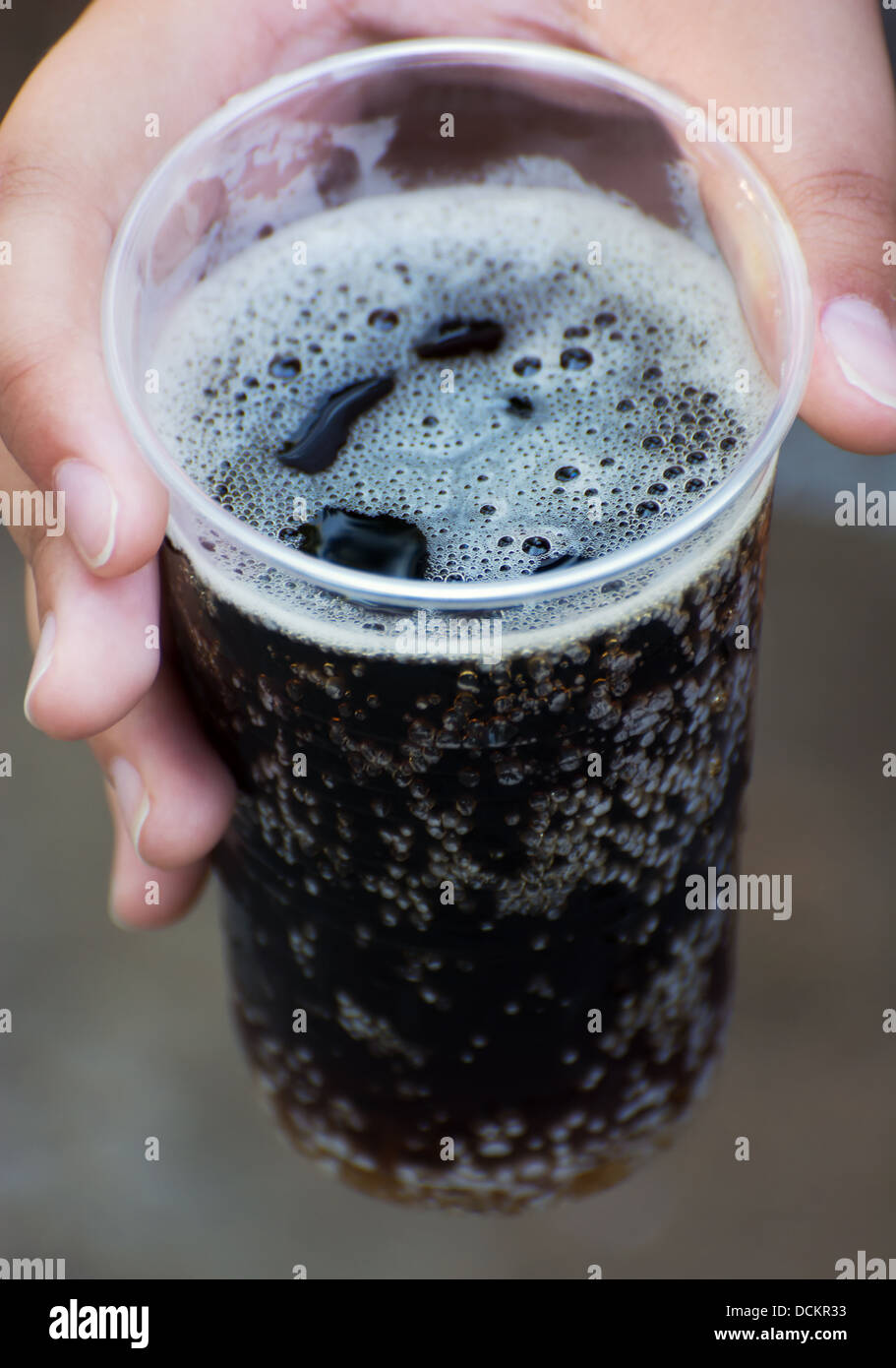 Hand holding a cup with fizzy drink Stock Photo - Alamy