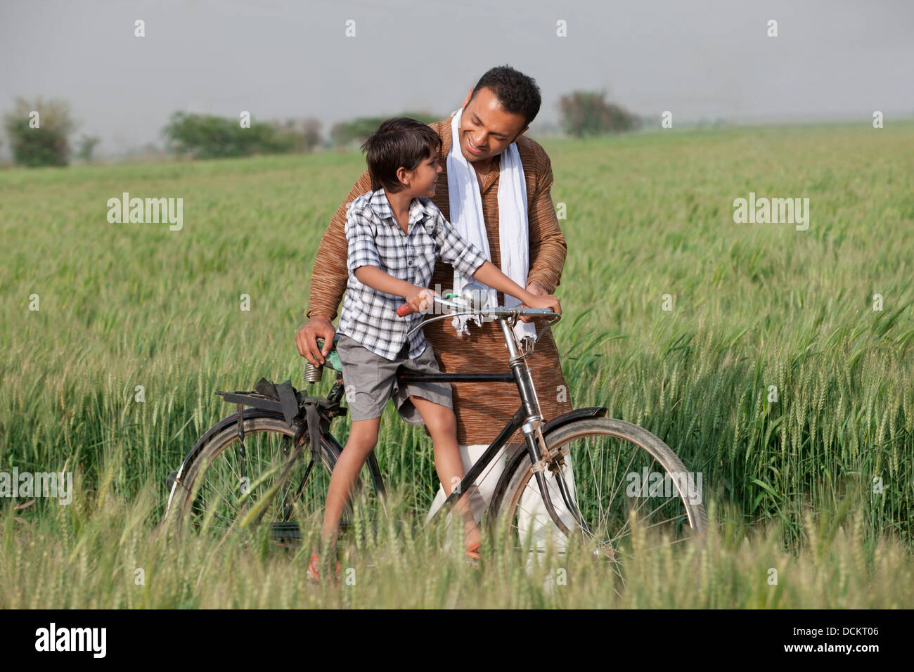 Father guiding son to ride cycle in the field Stock Photo - Alamy