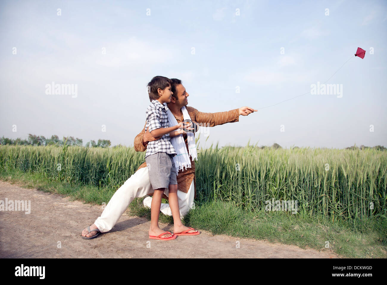 Happy father and son flying a kite in field Stock Photo - Alamy
