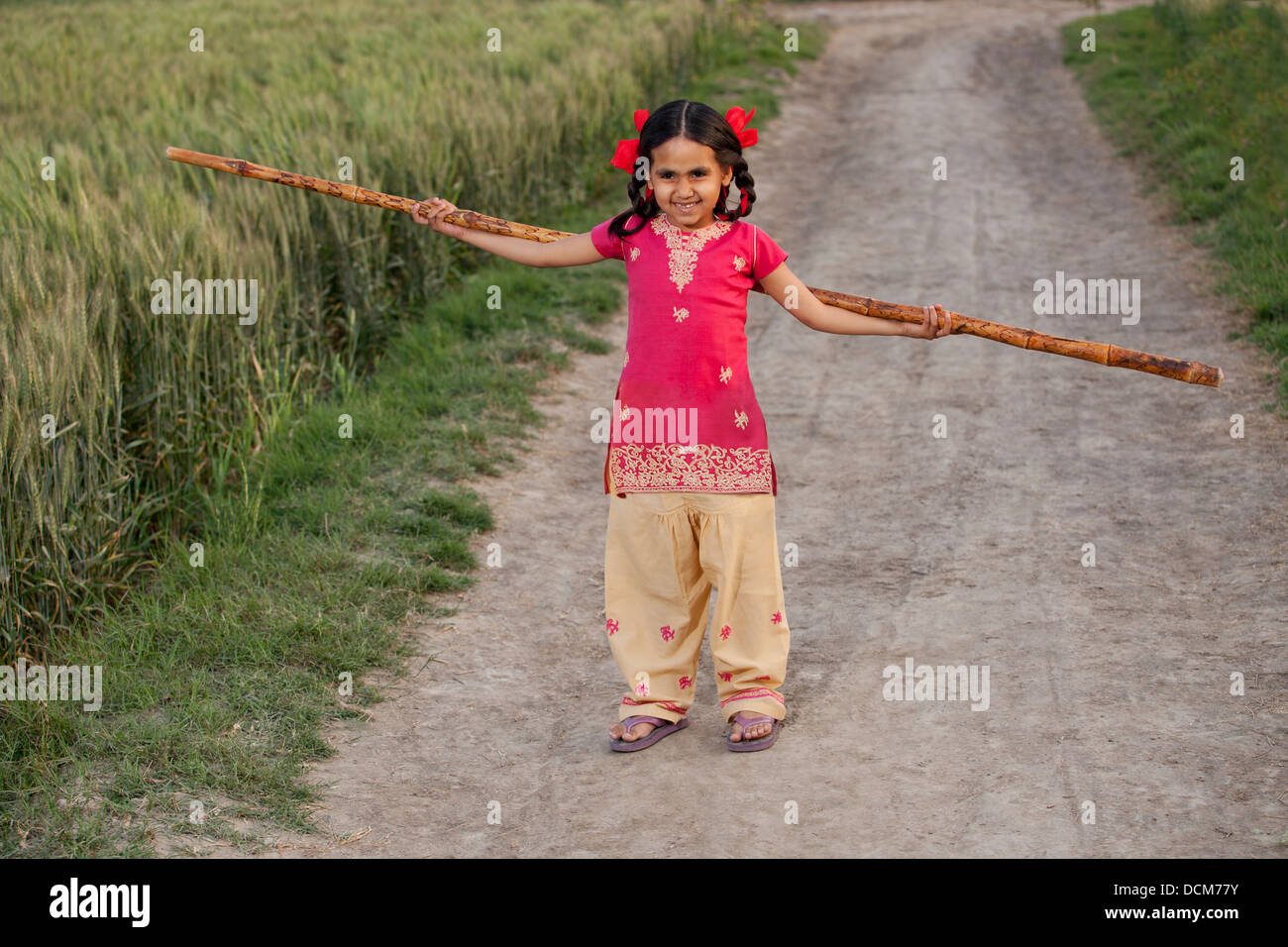 Full length of an Indian girl holding a long stick Stock Photo - Alamy