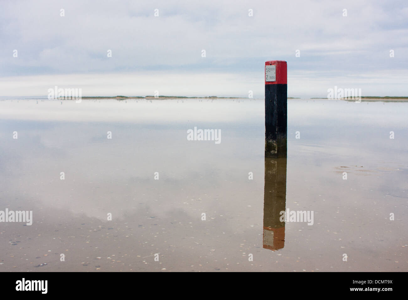 Red pole, reflected in calm sea at ebb tide Stock Photo - Alamy