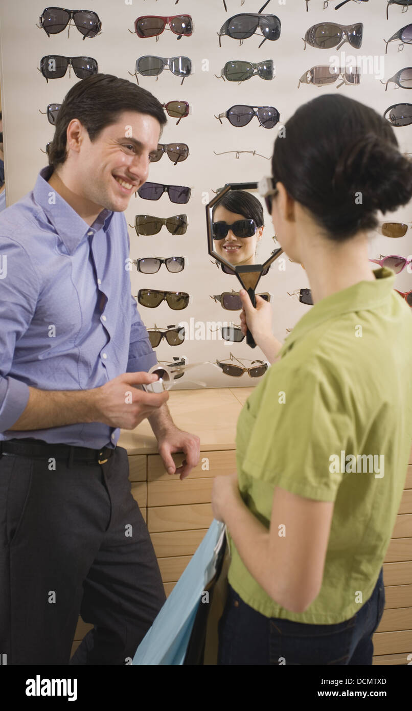 Woman trying on sunglasses in store Stock Photo - Alamy