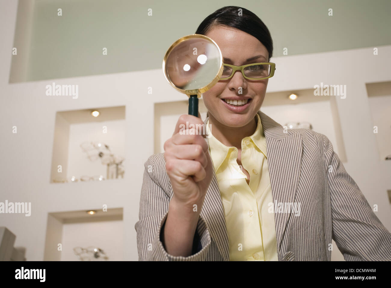 Woman with magnifying glass in store Stock Photo - Alamy