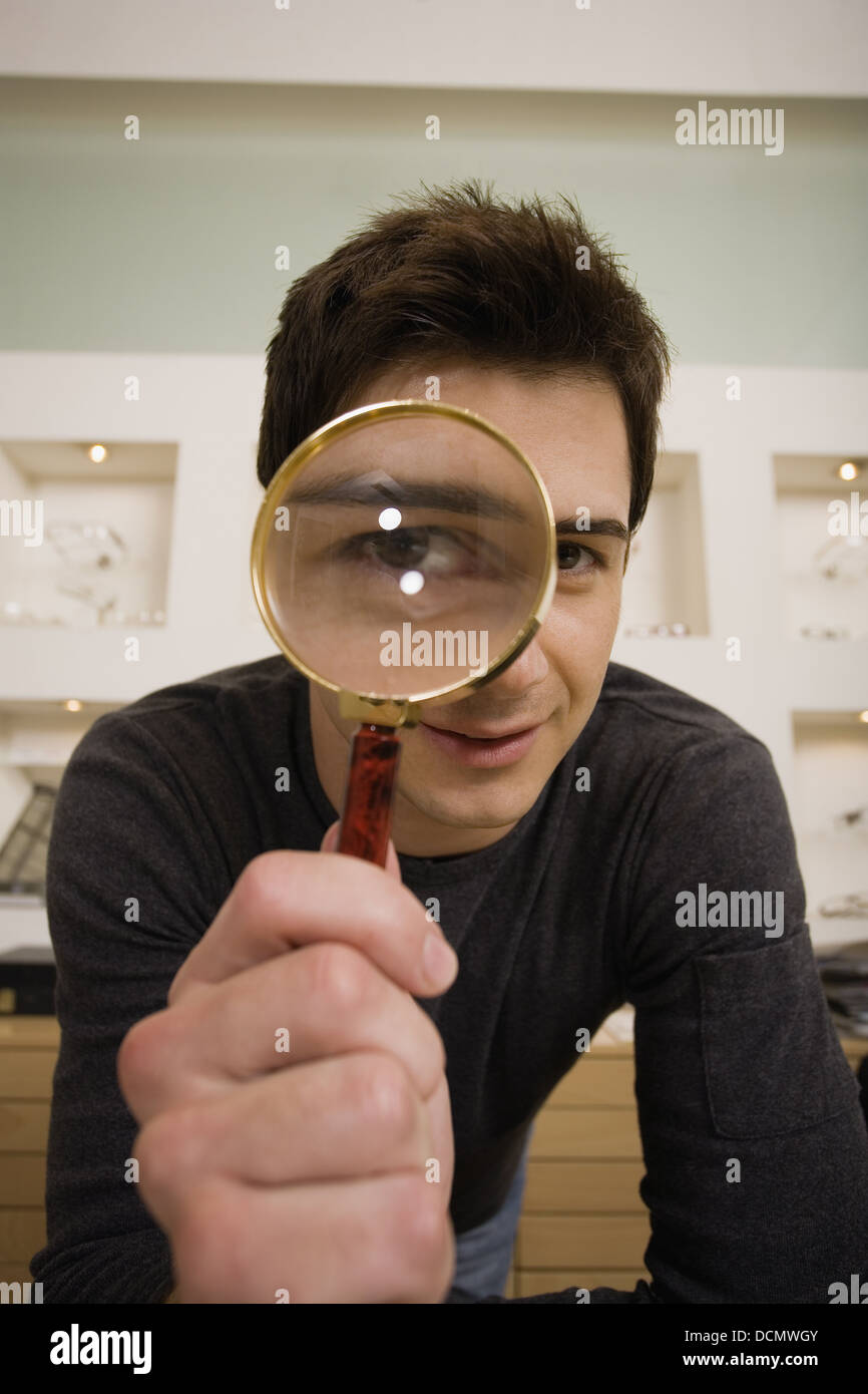 Man with magnifying glass on eye Stock Photo - Alamy