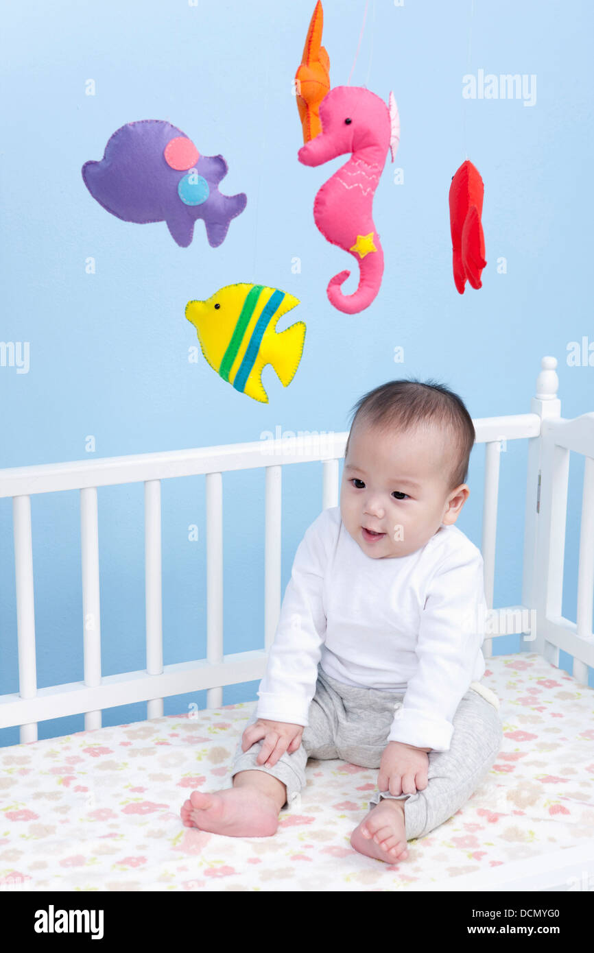 a baby inside a crib playing with mobile Stock Photo - Alamy