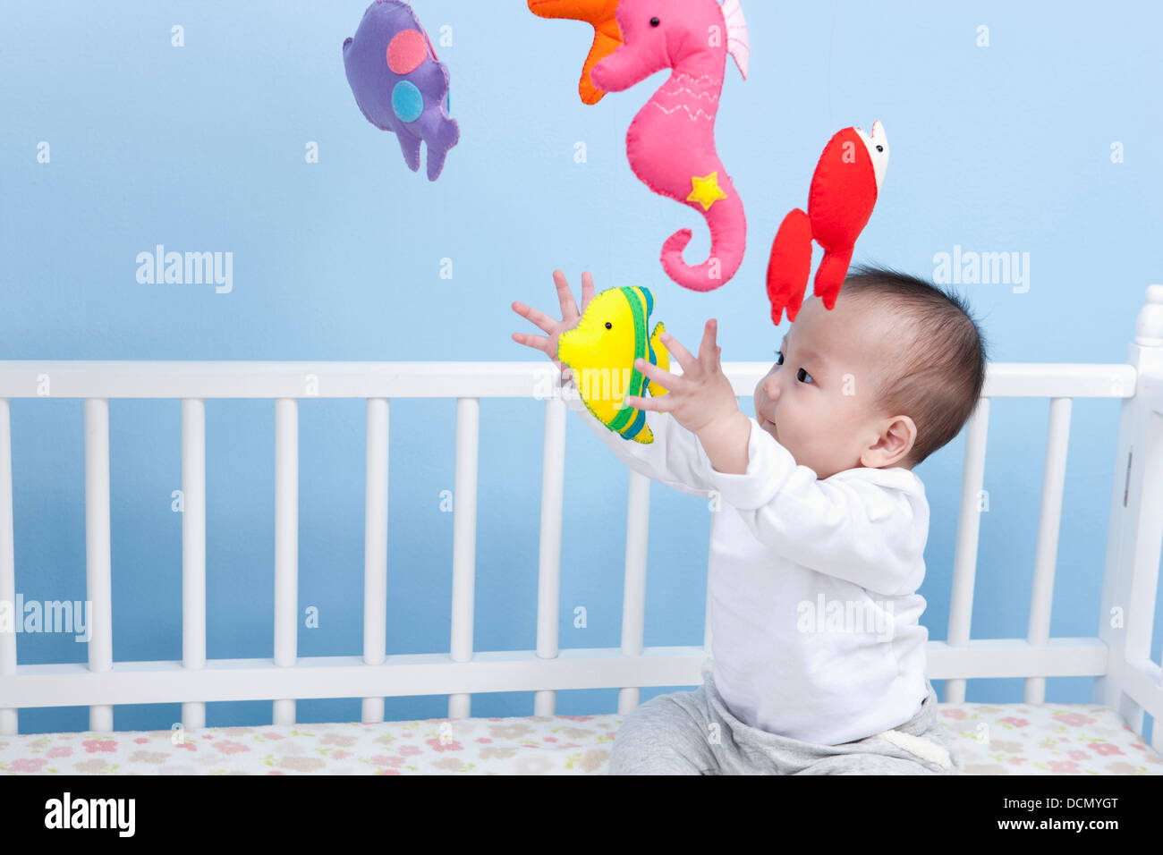a baby inside a crib playing with mobile Stock Photo - Alamy