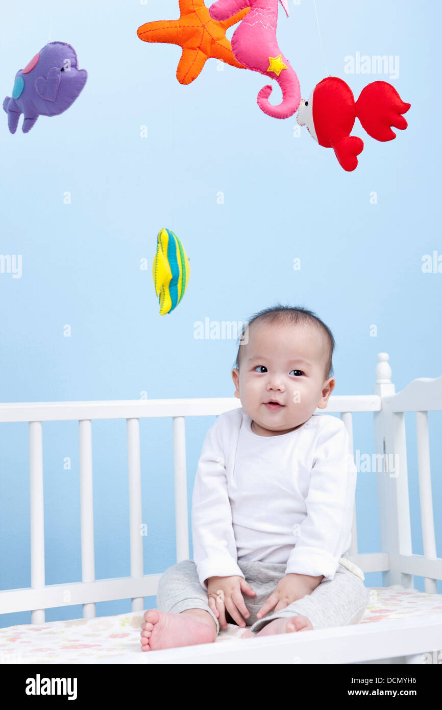 a baby inside a crib playing with mobile Stock Photo - Alamy