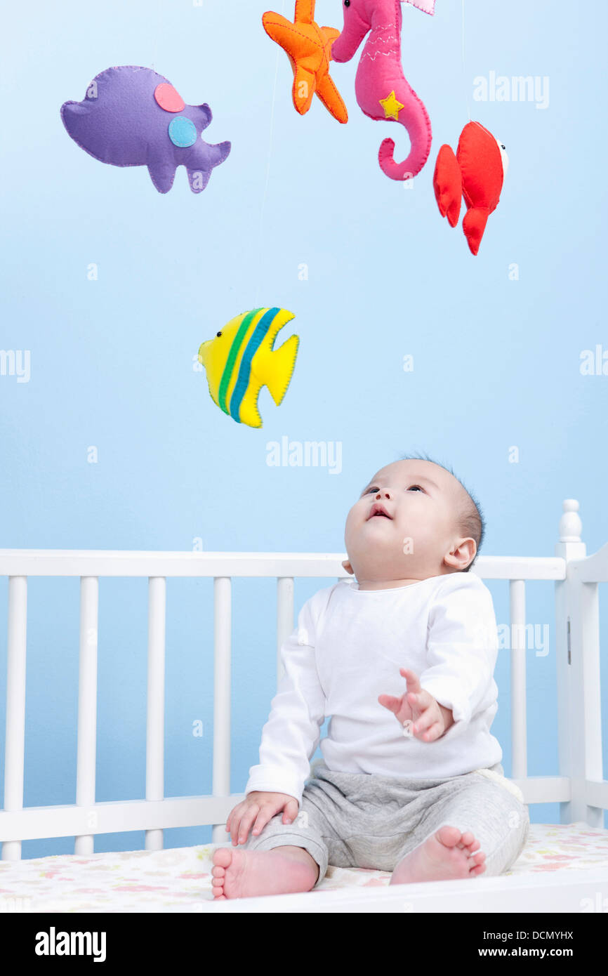 a baby inside a crib playing with mobile Stock Photo - Alamy