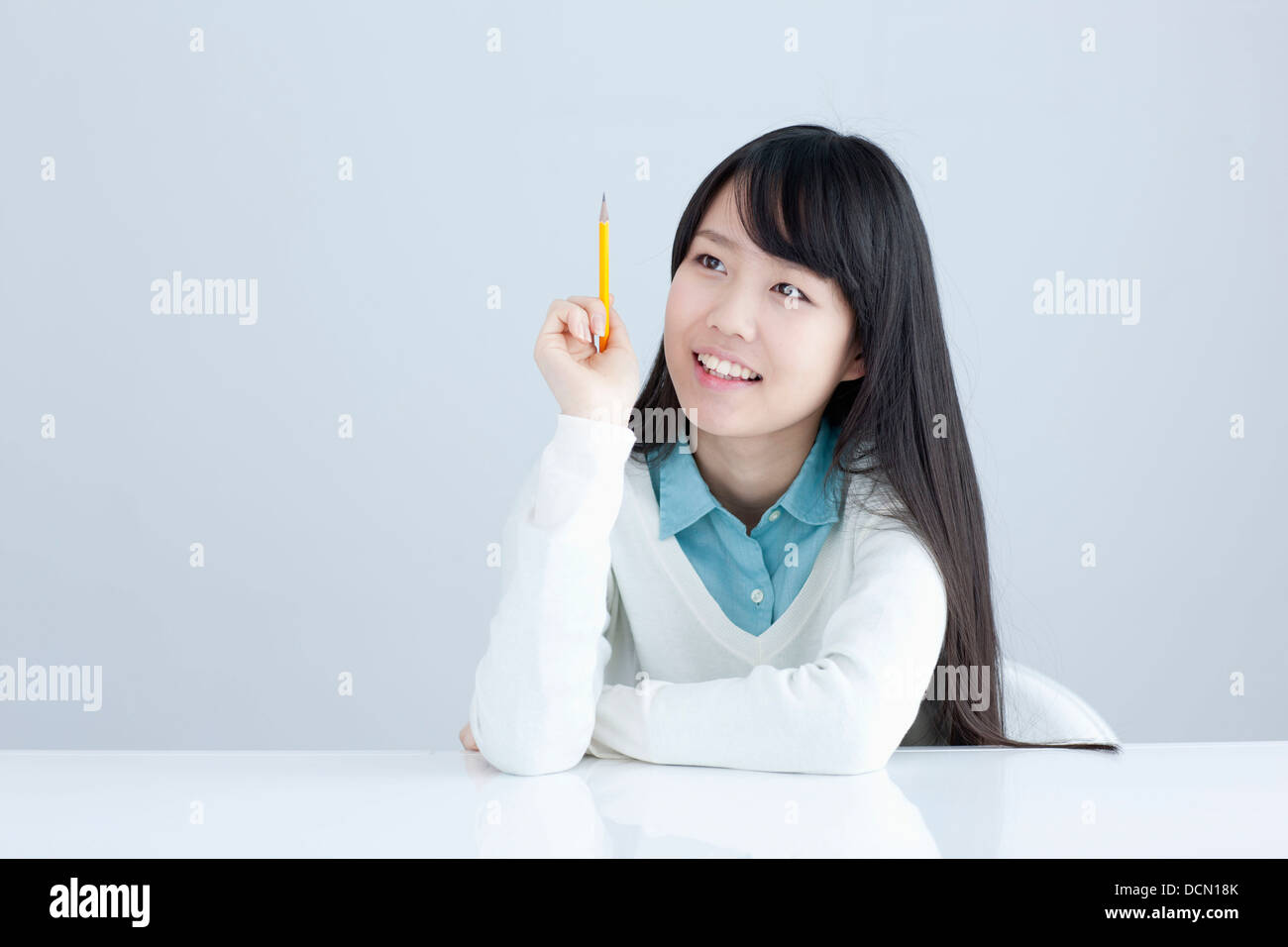 a lady leaning on a desk with a pencil Stock Photo - Alamy