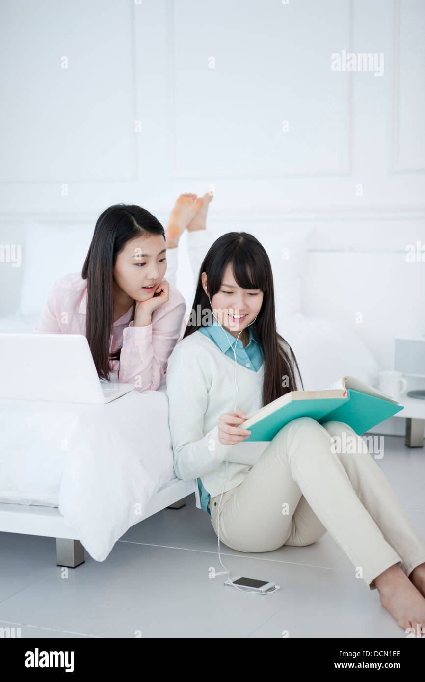 a lady using a laptop while other lady is reading a book Stock Photo ...