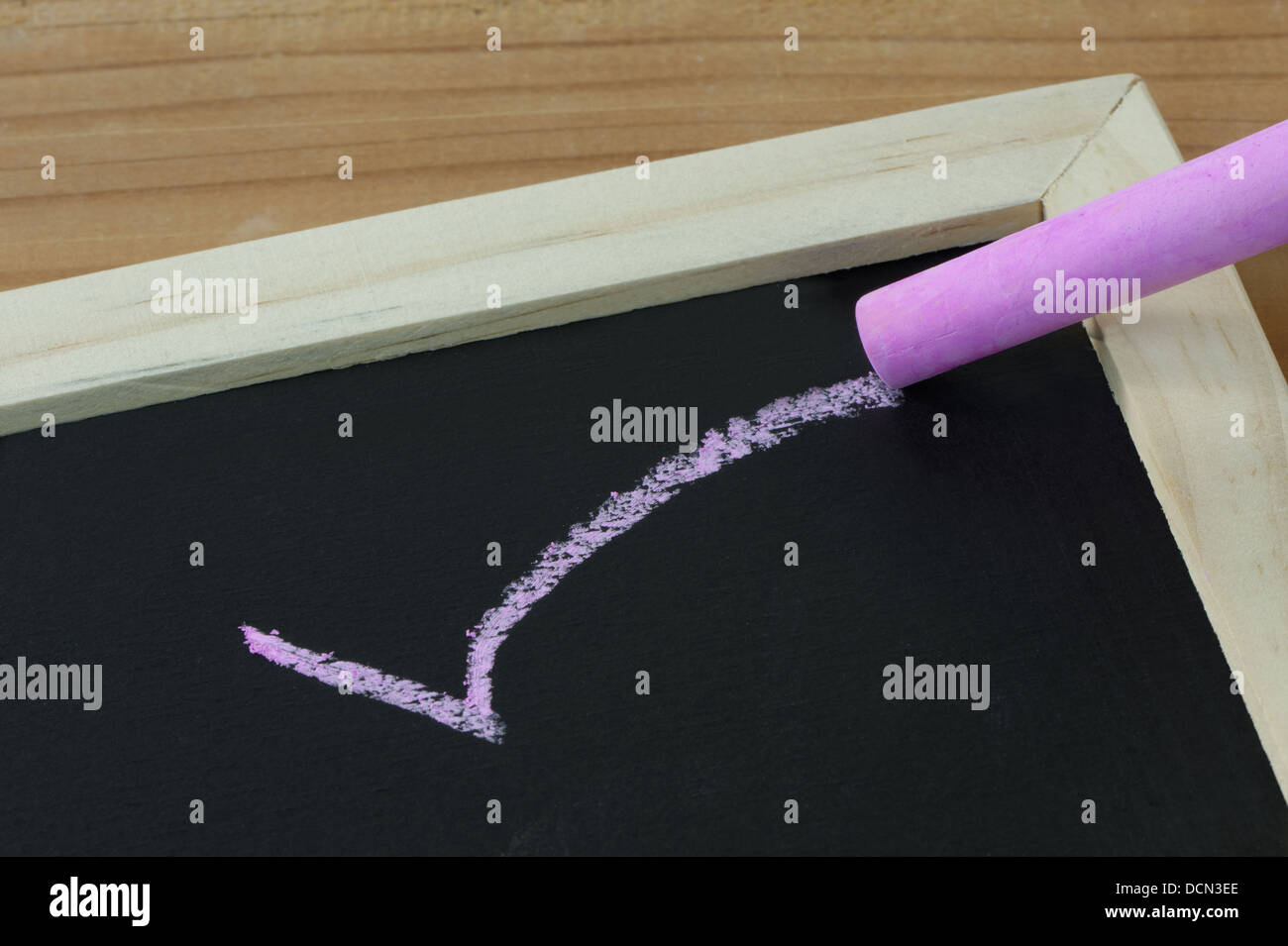A stick of chalk drawing a tick on a chalkboard Stock Photo - Alamy