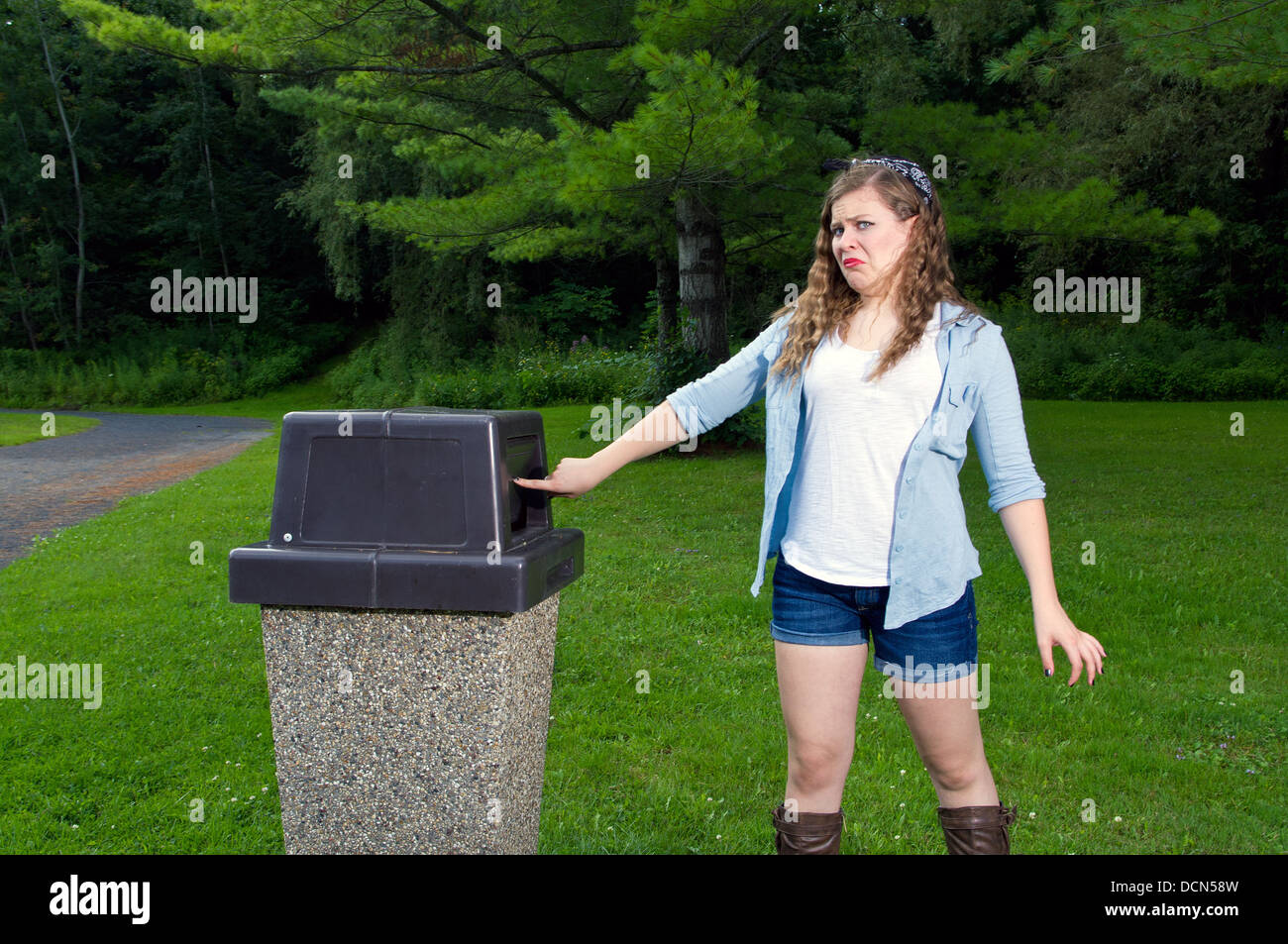 Teen Girl in a park looking in a trash can with a disgusting look on ...
