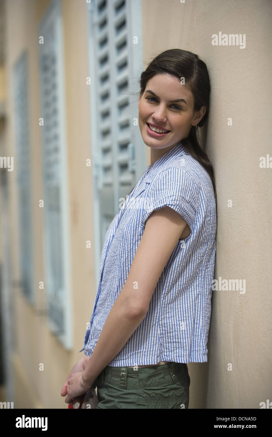Woman leaning against a wall Stock Photo - Alamy