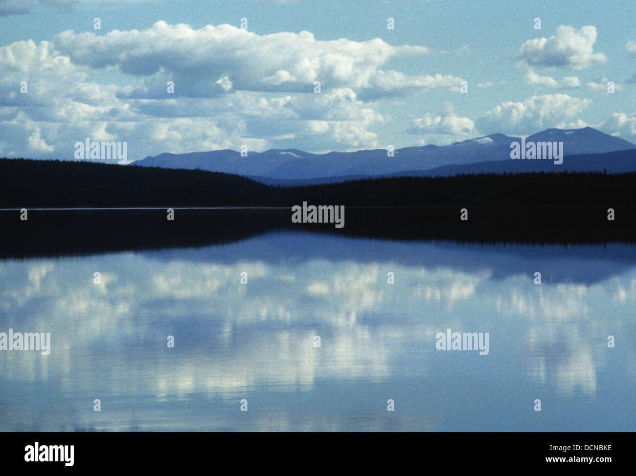 Clouds, mountains and forest reflect in Lake Teslin, Yukon Territory ...