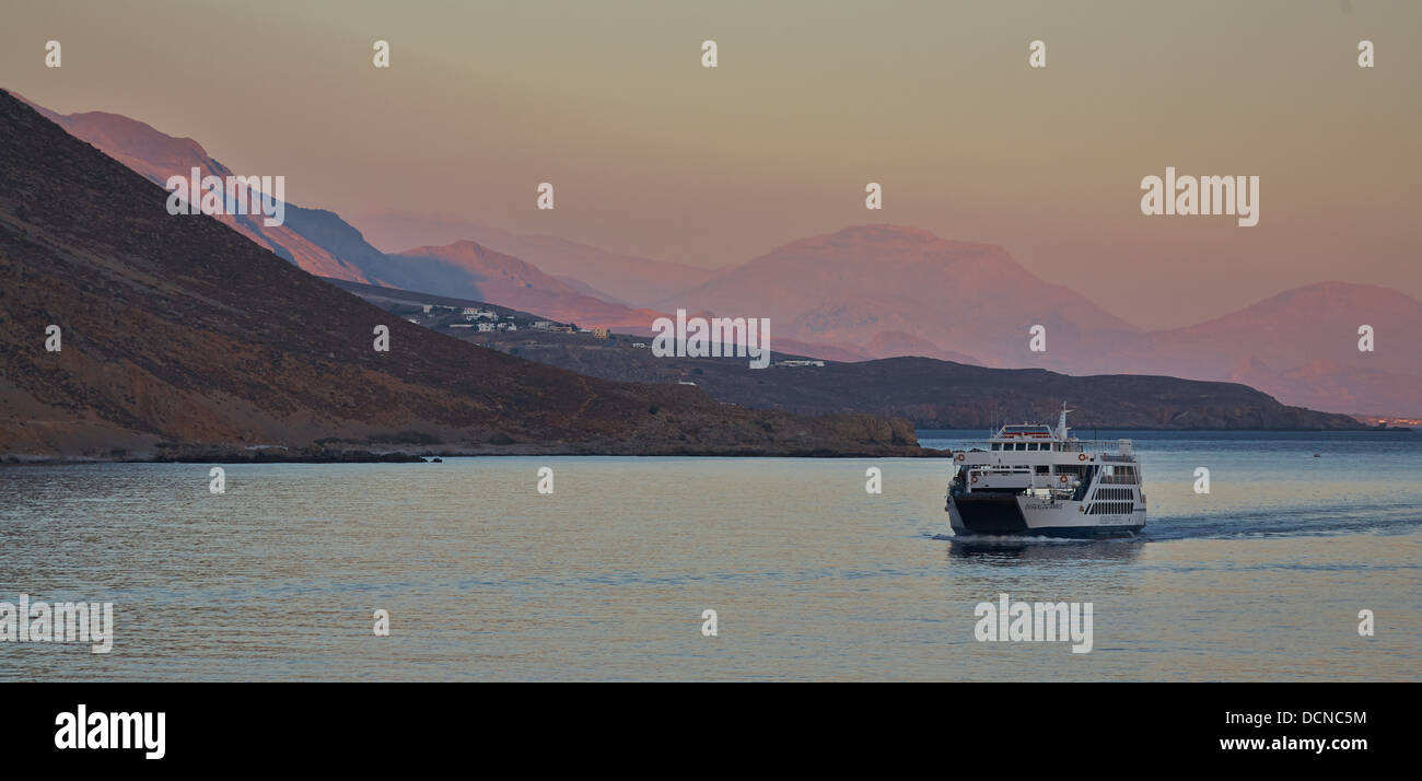 A Greek ferry sailing along the shores of South West Crete at dusk with ...