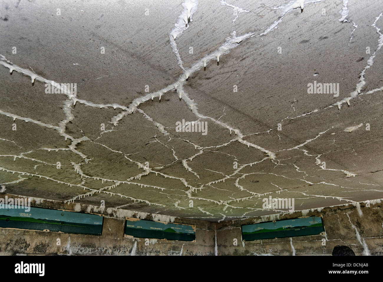 White mineral deposits hanging like stalactites from the concrete ...