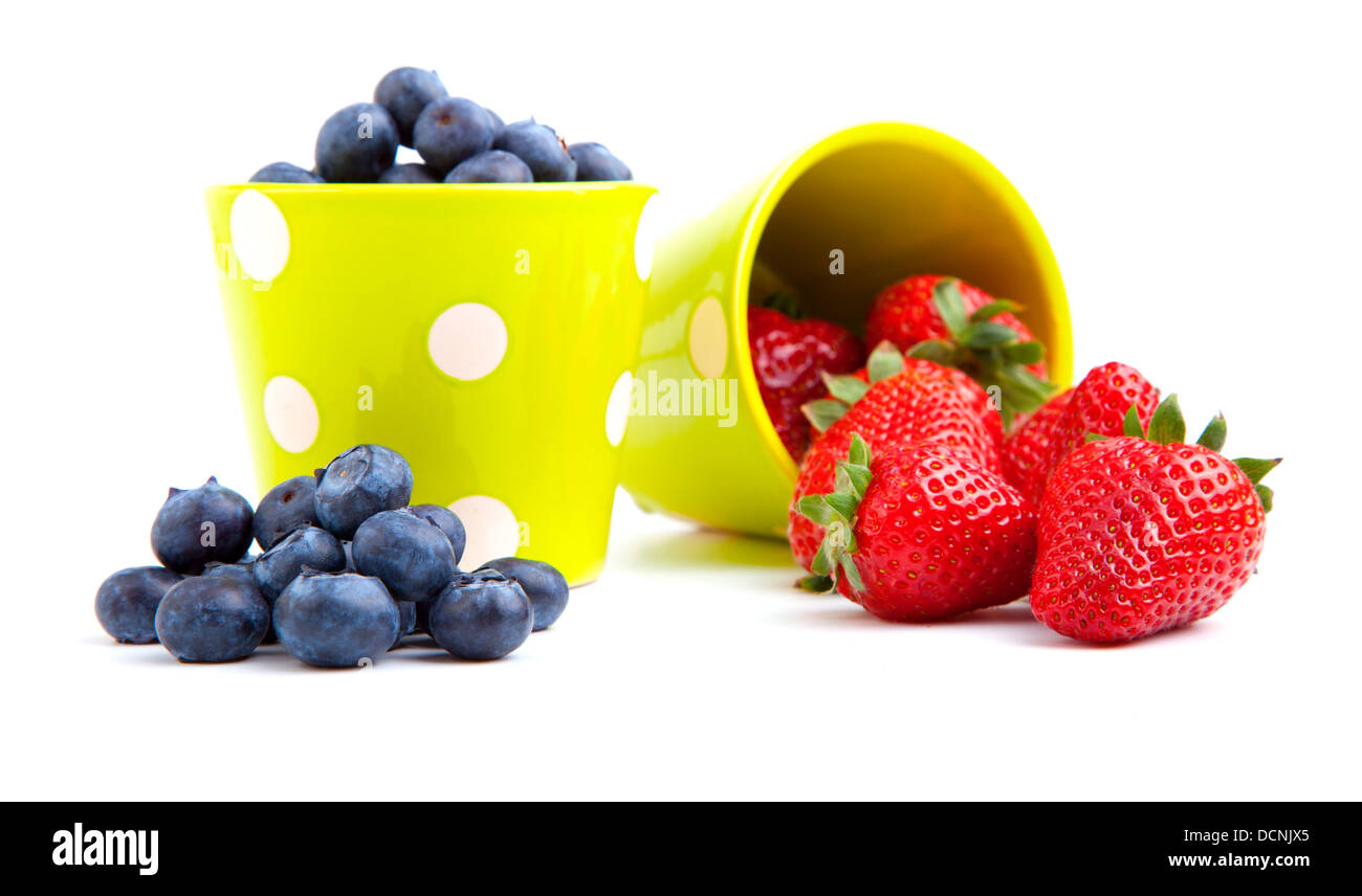 Assorted fresh picked berries in a green mug over a white backgr Stock ...