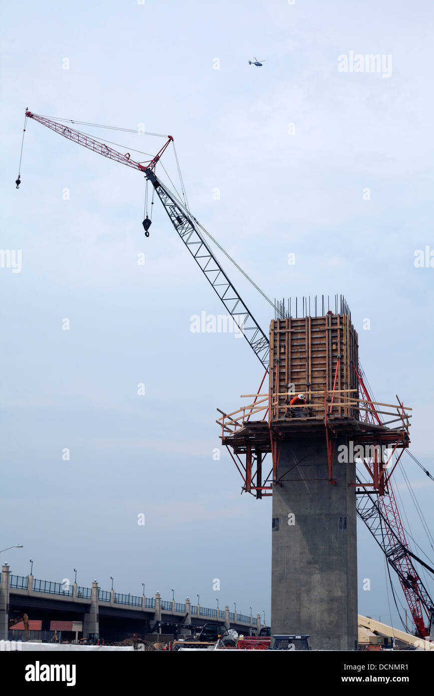 Man working on vertical concrete structure, with crane behind Stock ...