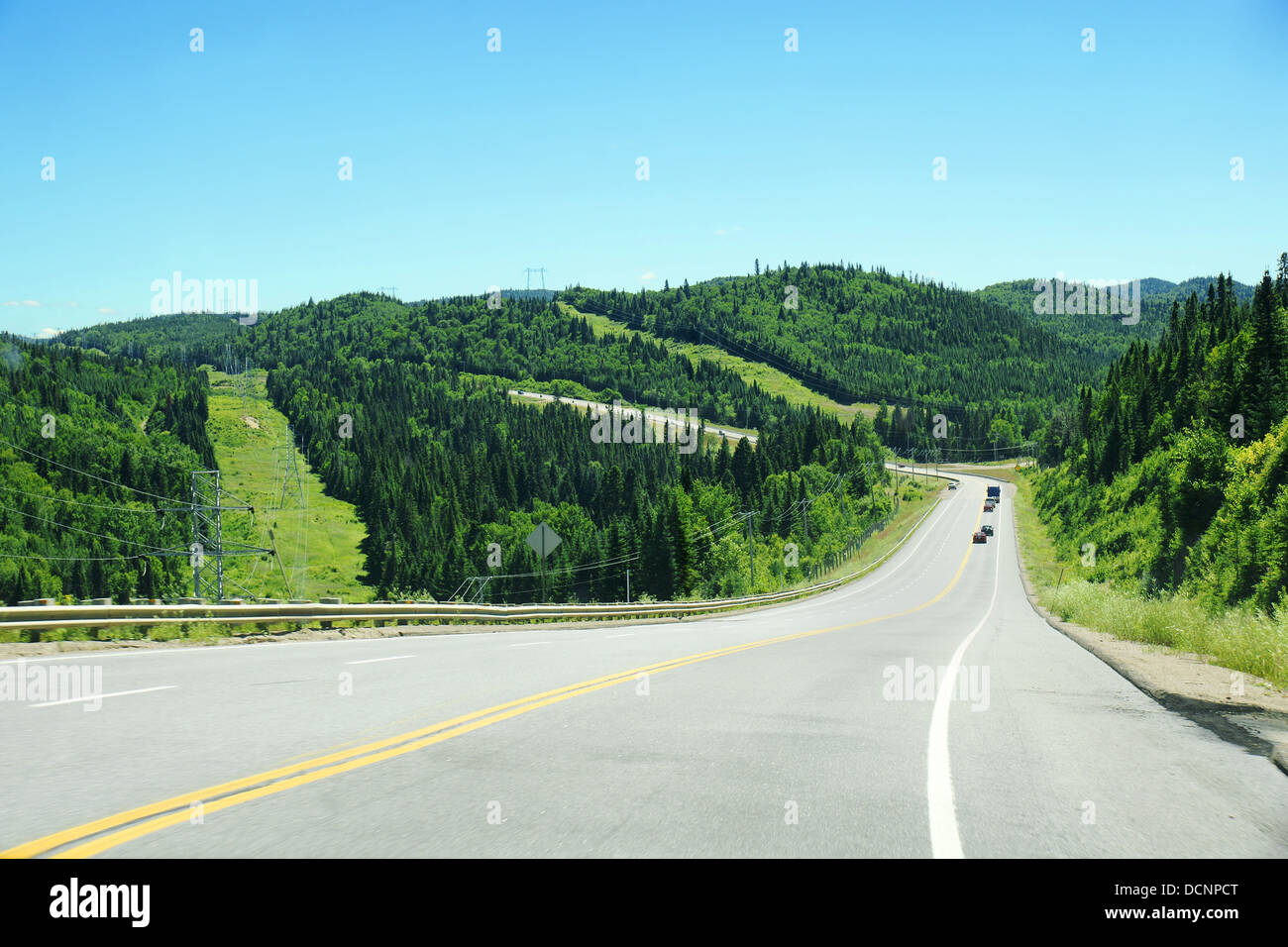 Downhill road with mountains and coniferous trees Stock Photo - Alamy