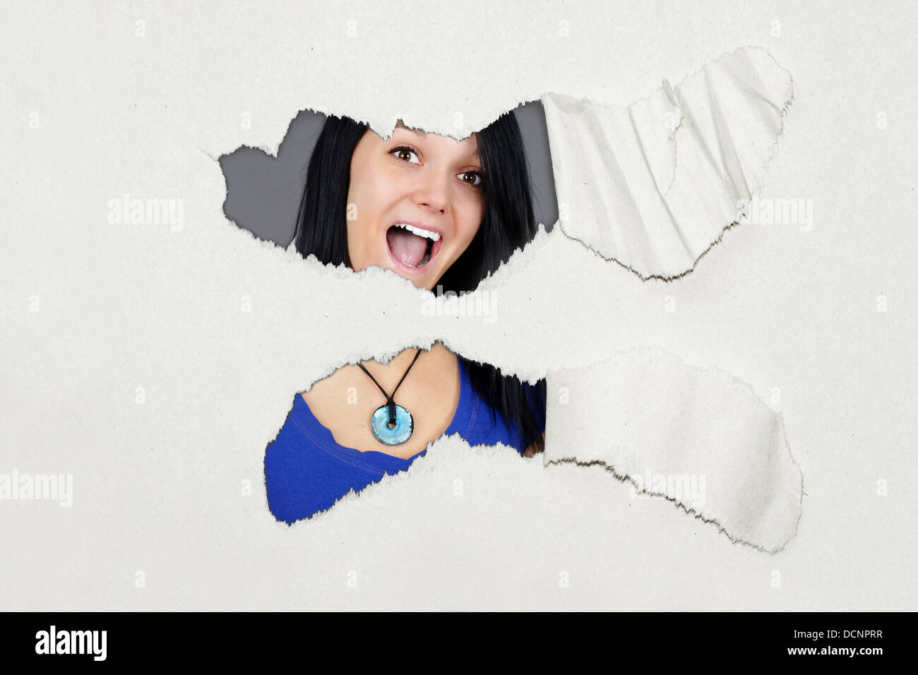 Surprised young woman under ripped paper Stock Photo - Alamy