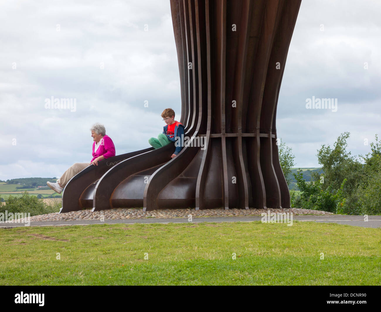 A senior lady and a boy sit on the foot of the massive Angel of the ...