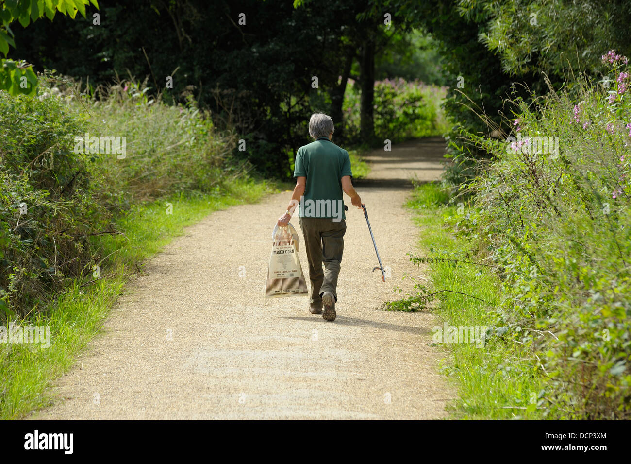 Nature reserve worker litter picking along the public footpath ...