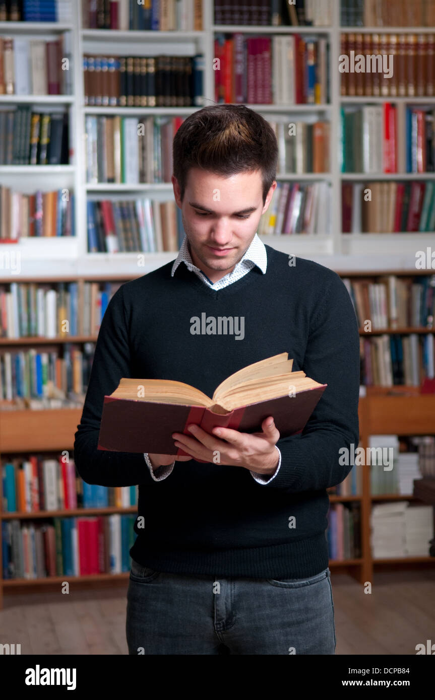 Male sudent standing in library, holding book Stock Photo - Alamy