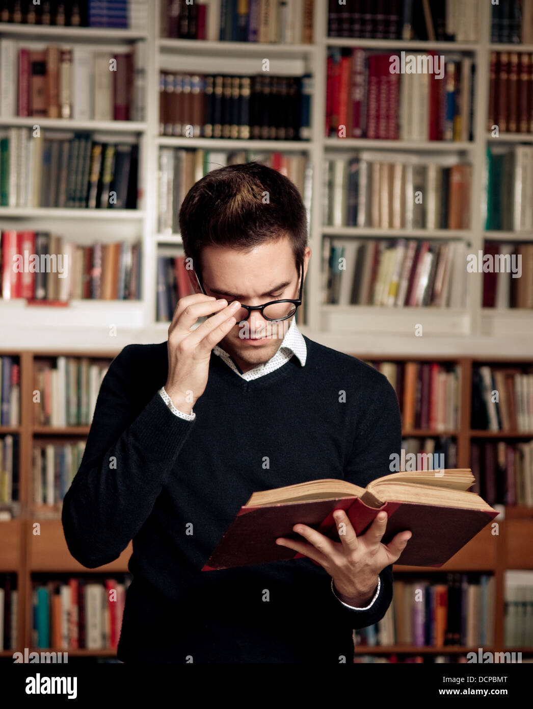 Serious young college student reading book in library Stock Photo - Alamy