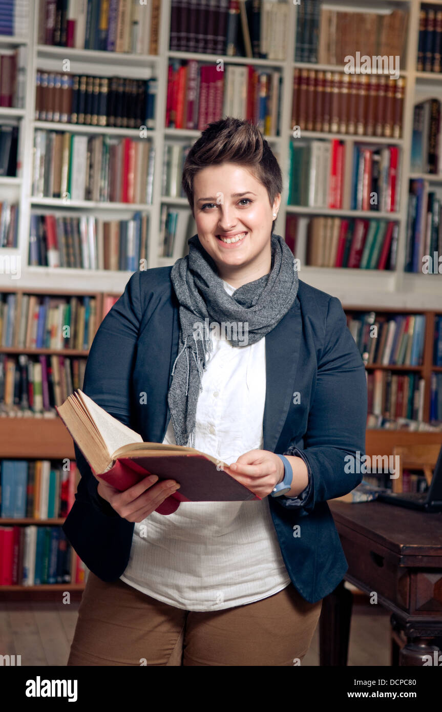 Smiling female college student holding open book Stock Photo - Alamy