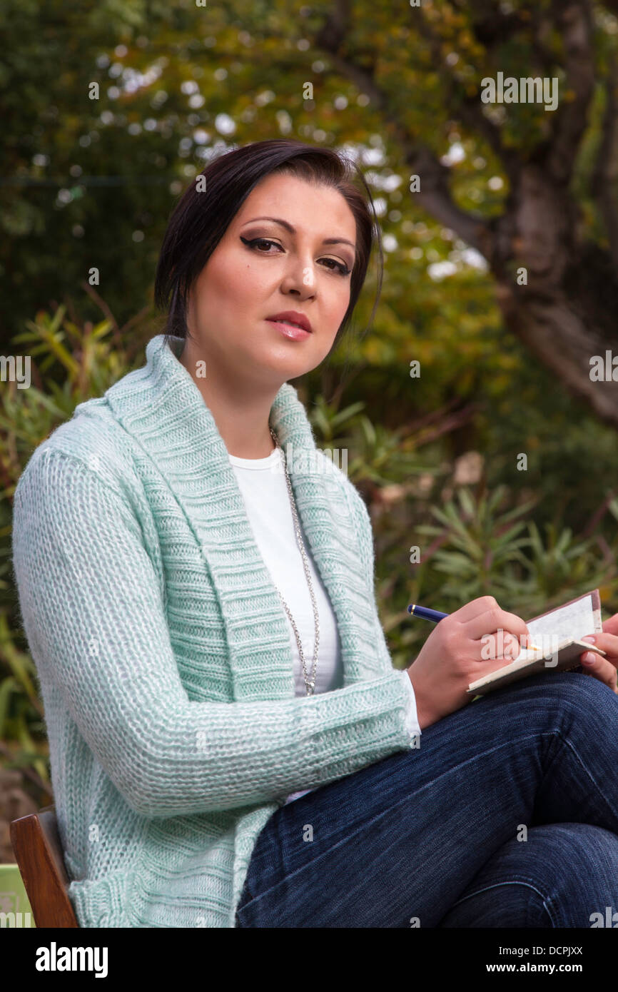 View of a beautiful young woman writing her diary on a park Stock Photo ...