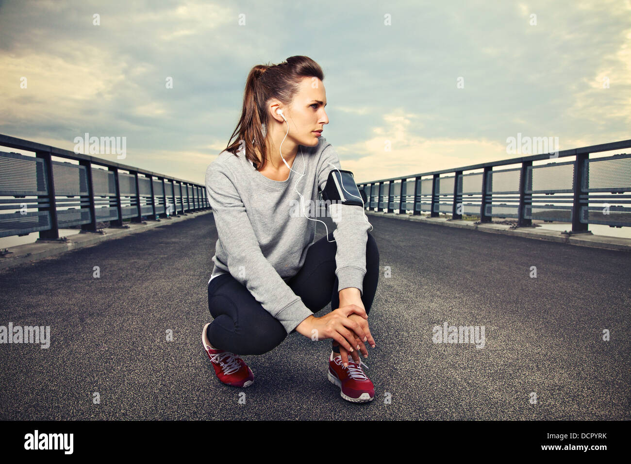 Female fitness runner sitting alone on the bridge resting Stock Photo ...