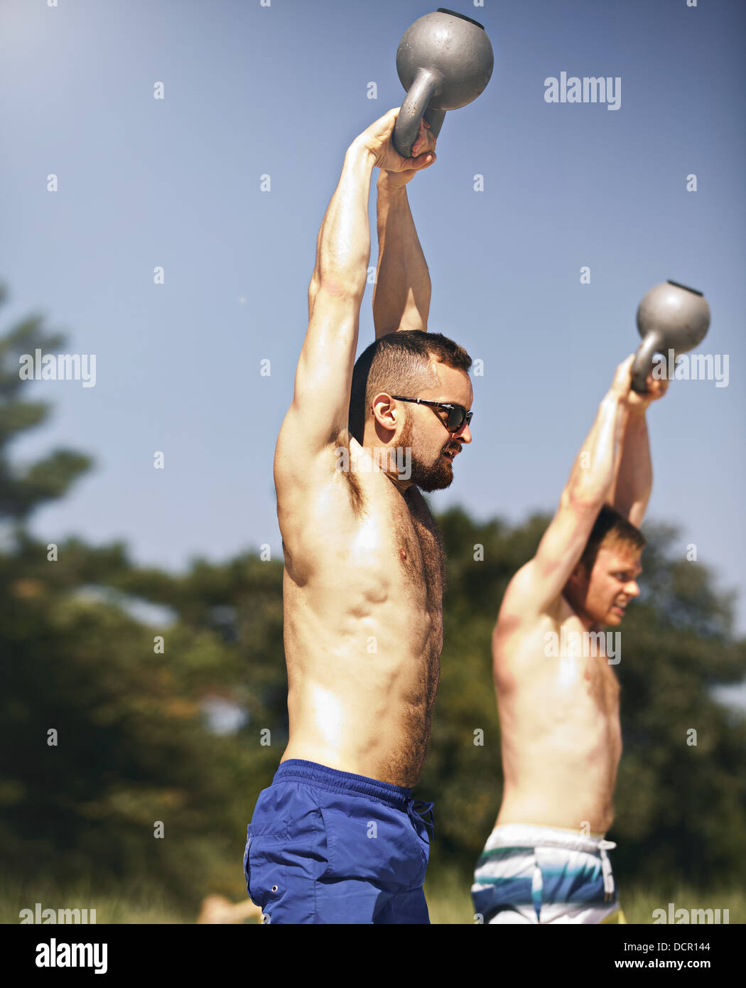 Two strong young men lifting heavy kettlebell weights Stock Photo - Alamy