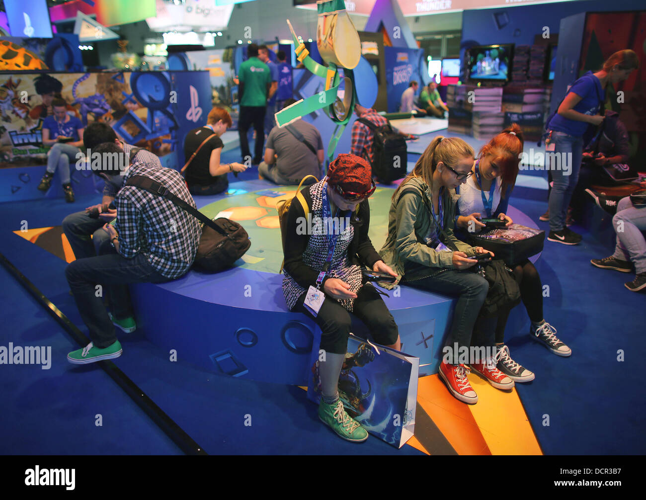 Cologne, Germany. 21st Aug, 2013. People test games at a booth of Sony ...