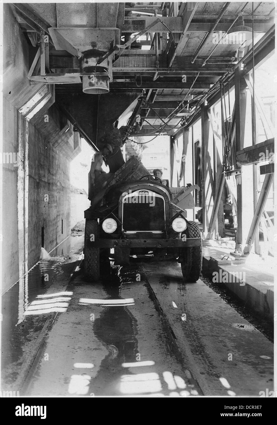 This photograph shows workers loading concrete into 2-yard bottom dump ...