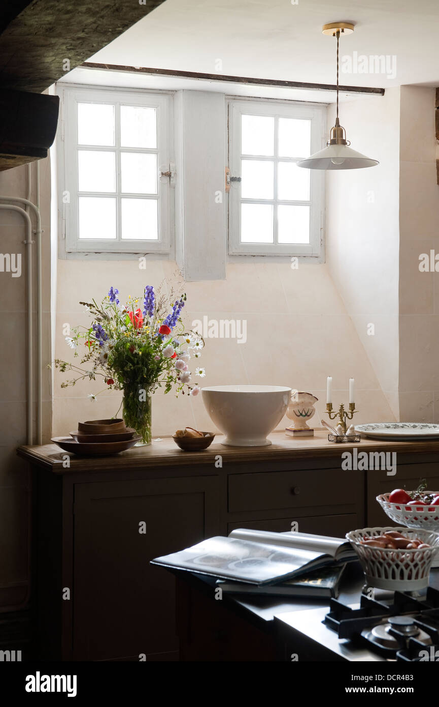 Paneled window above a wooden sideboard adjacent to an island hob unit ...
