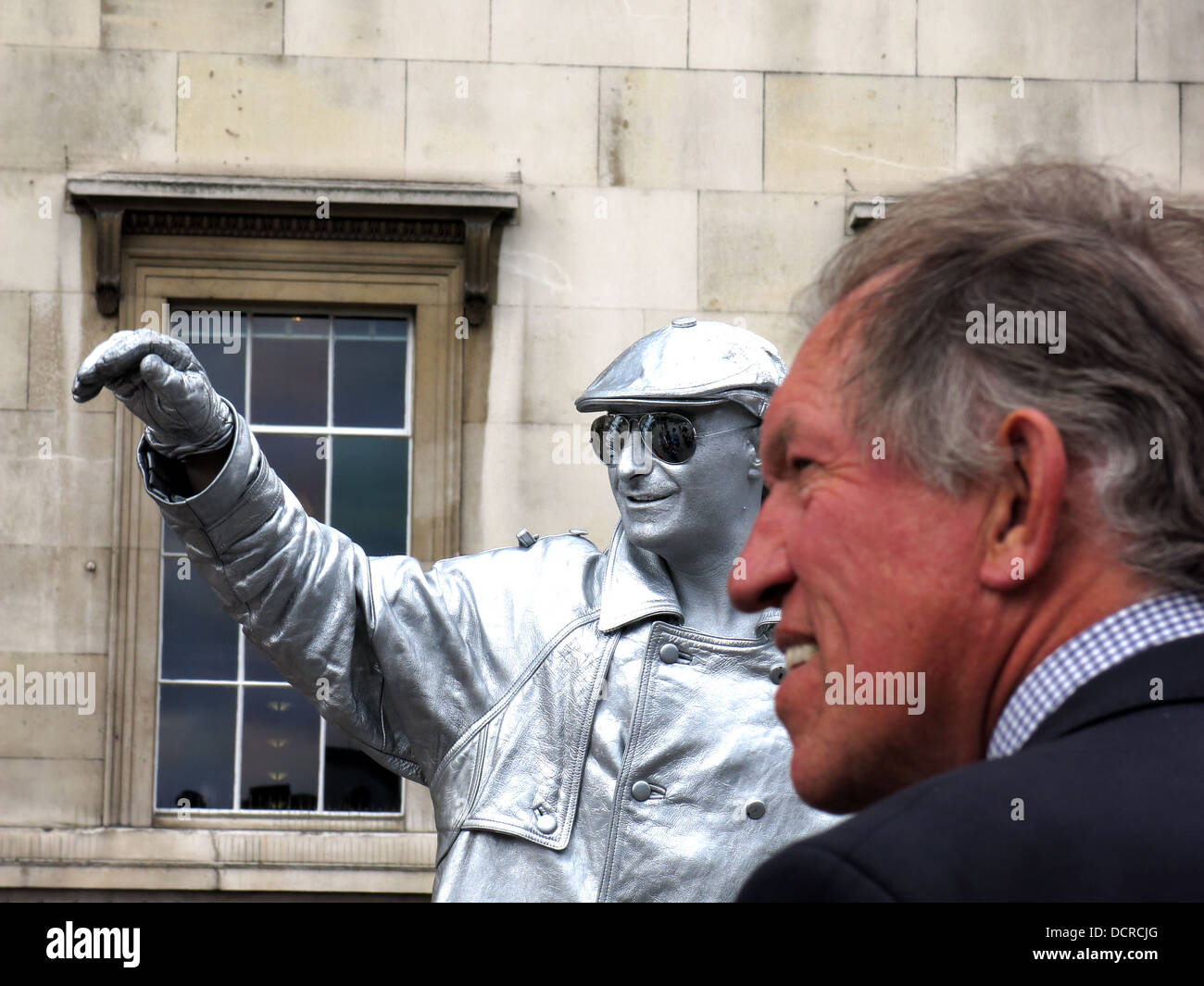 Street performer busker dressed in silver entertains a crowd in ...