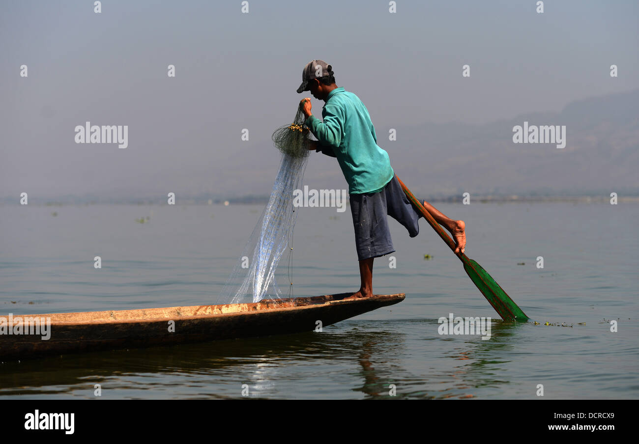 A fisherman on Inle Lake uses his leg to row his boat Stock Photo - Alamy