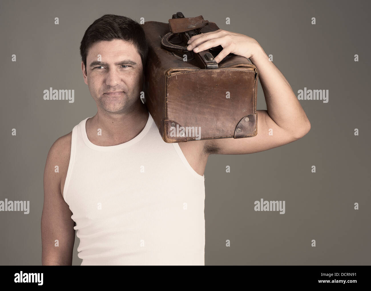 Determined man in white tank top holding brown leather luggage bag on ...