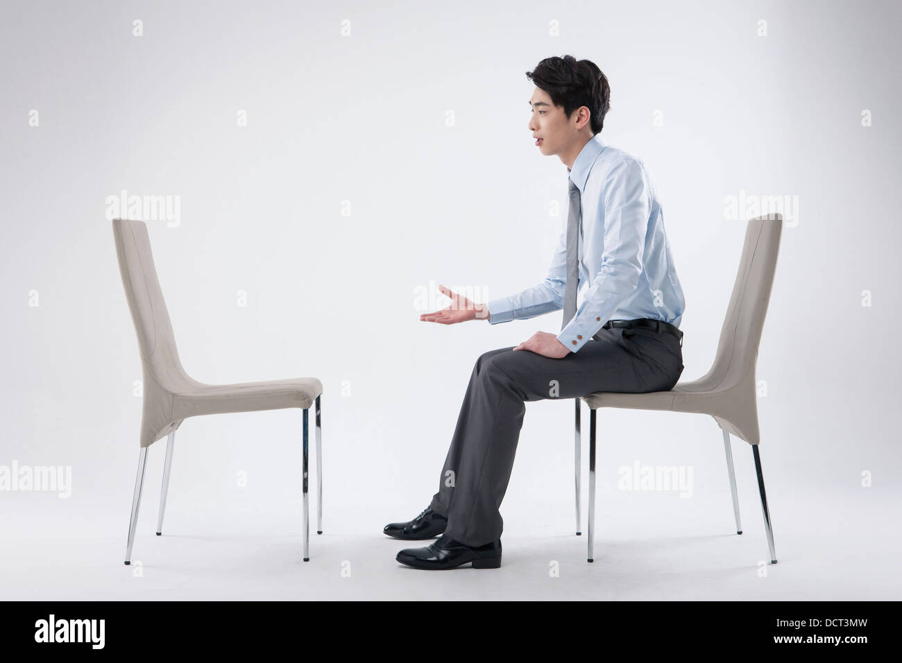 a business man sitting and talking to an empty chair Stock Photo - Alamy