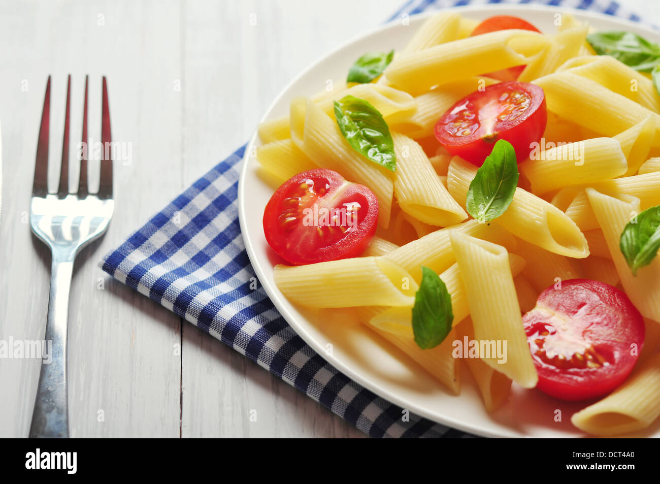 Penne pasta with cherry tomatoes and basil closeup Stock Photo - Alamy