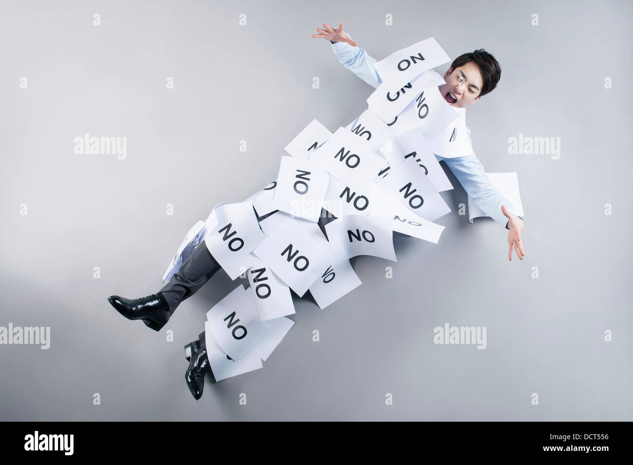 a business man covered by papers that say no Stock Photo - Alamy
