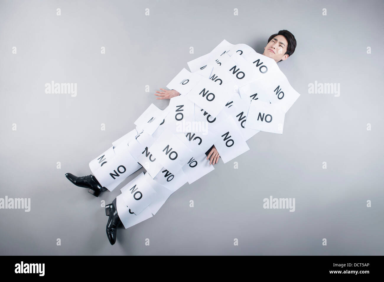 a business man covered by papers that say no Stock Photo - Alamy