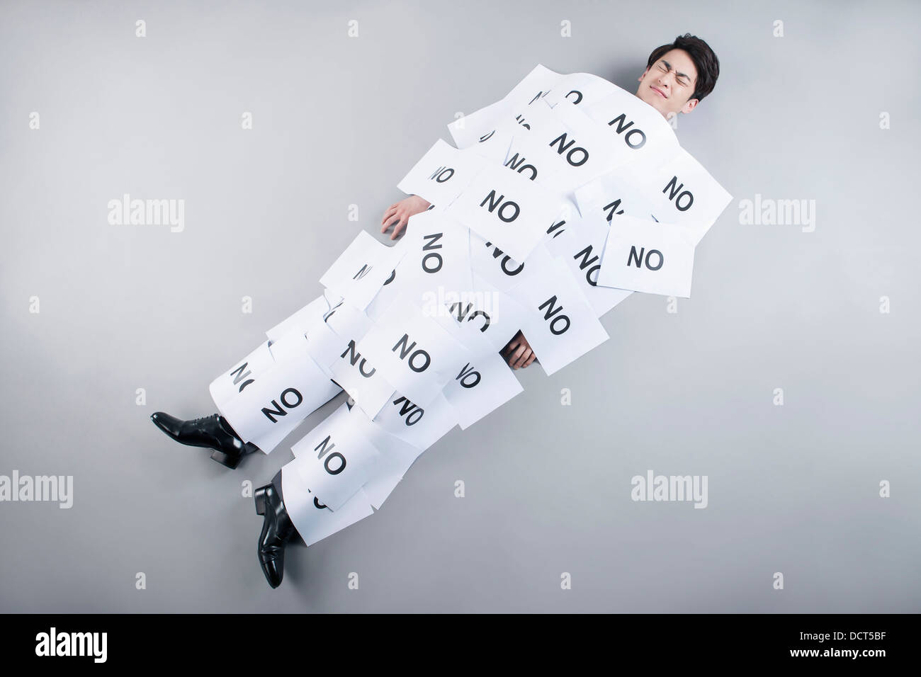 a business man covered by papers that say no Stock Photo - Alamy