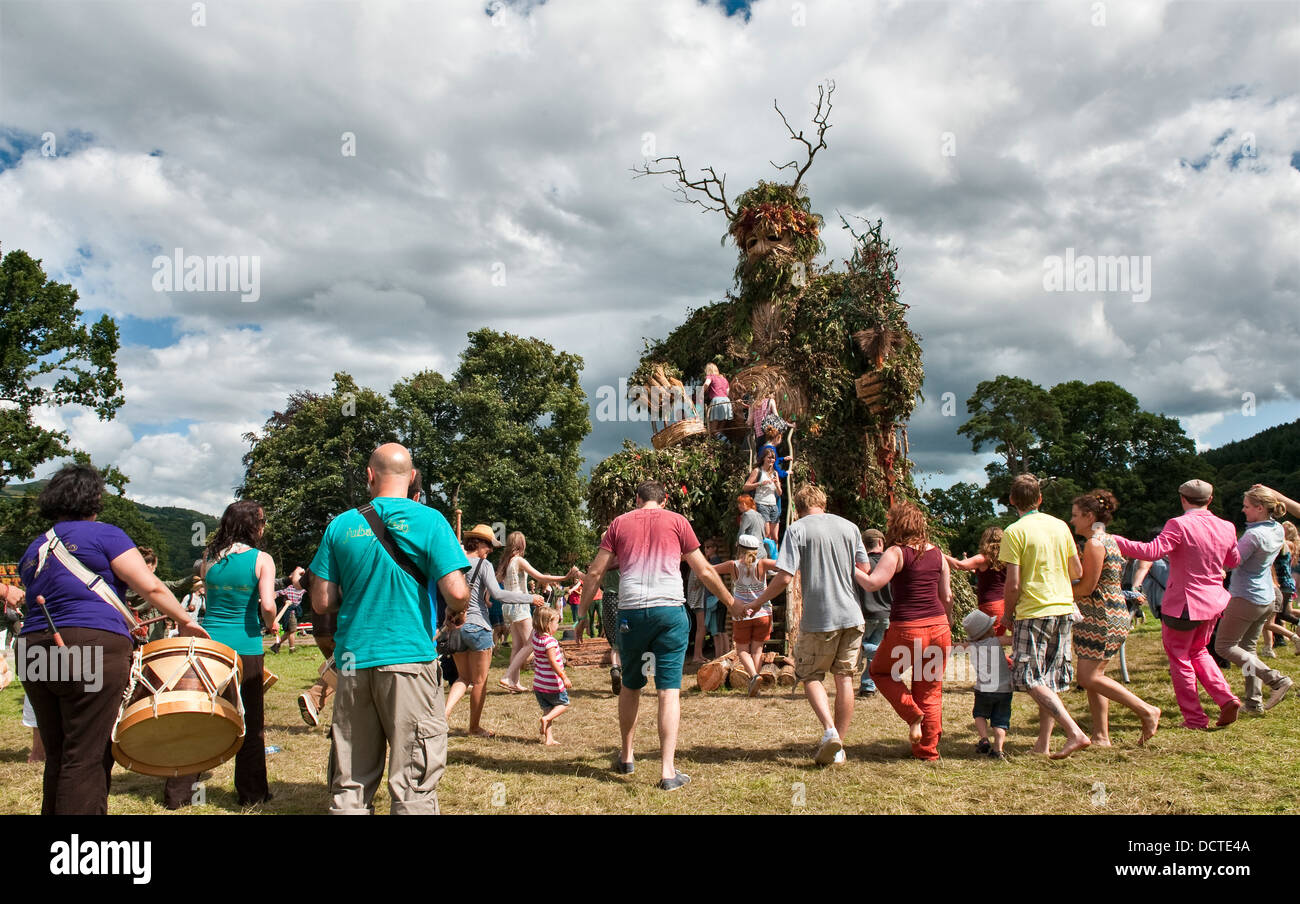 Festival goers circle dancing around a giant Green Man sculpture at the ...