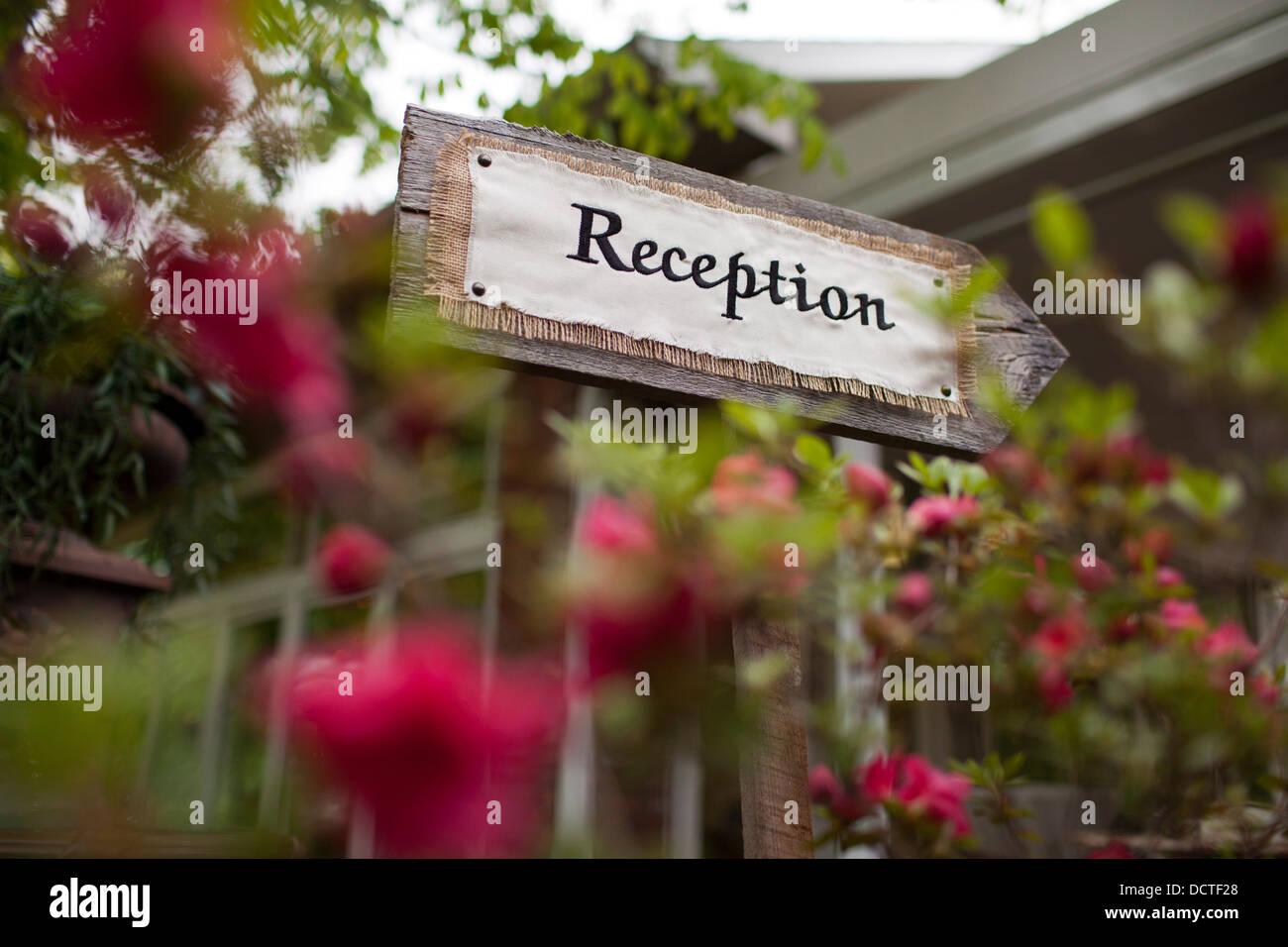 A wood, burlap and cotton sign directing guests to a wedding reception ...