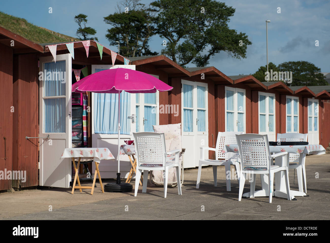 Beach hut with tables, chairs and umbrella set out on a summers day in ...