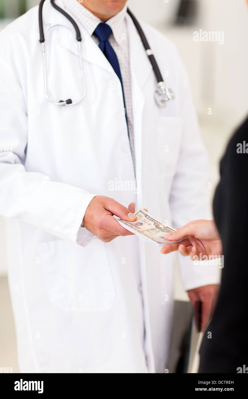 male medical doctor receiving money from a patient Stock Photo - Alamy