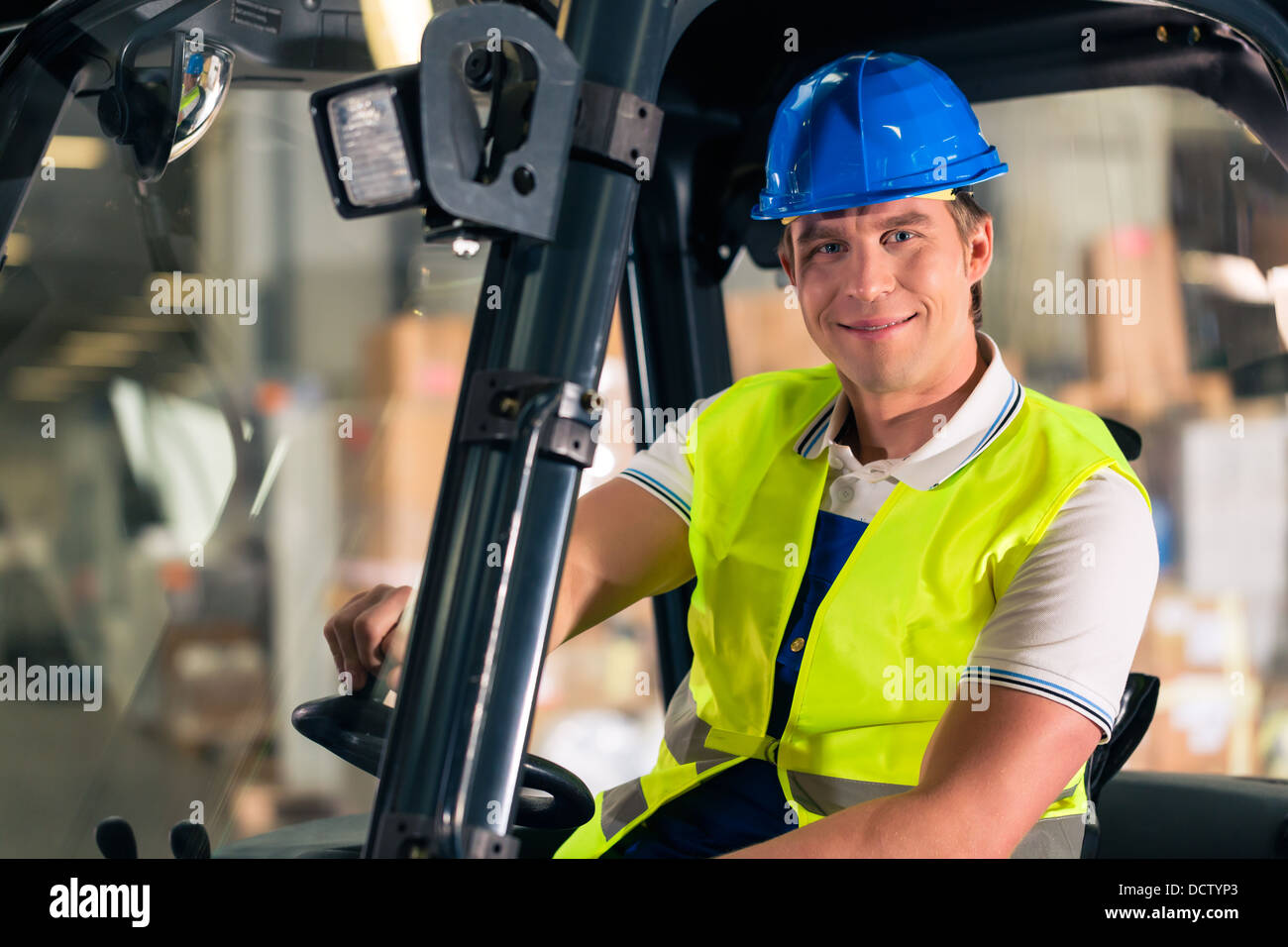 forklift driver in protective vest and forklift at warehouse of freight ...