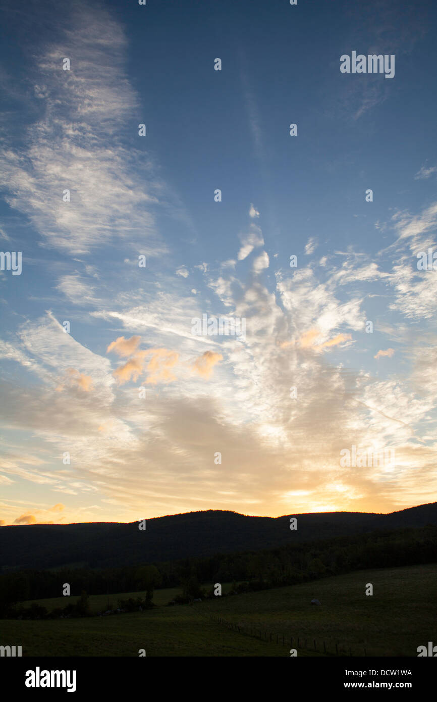 The clouds are backlit by the sun as it rises on a summer morning Stock ...