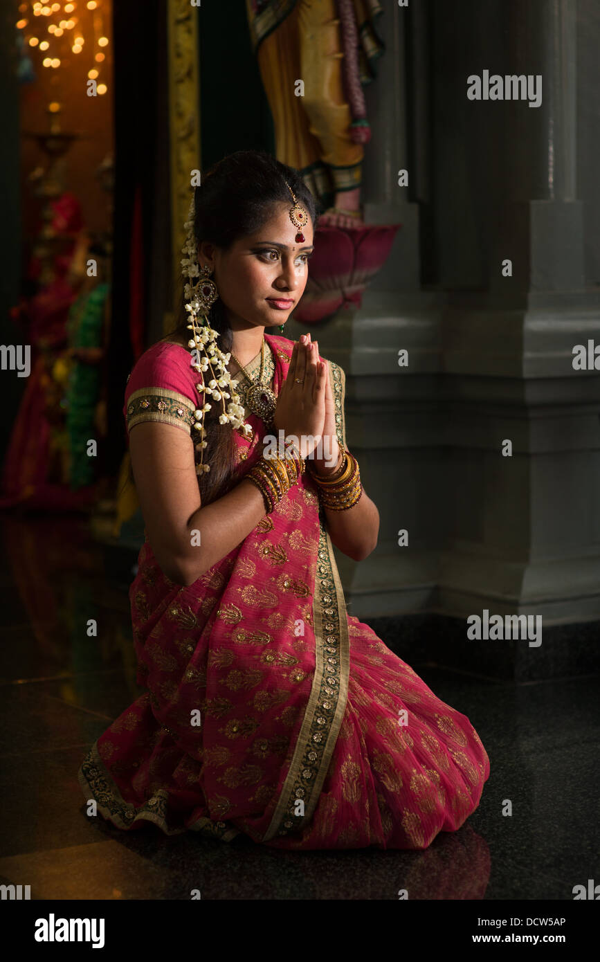 Young Indian woman in traditional sari dress praying in a hindu temple ...